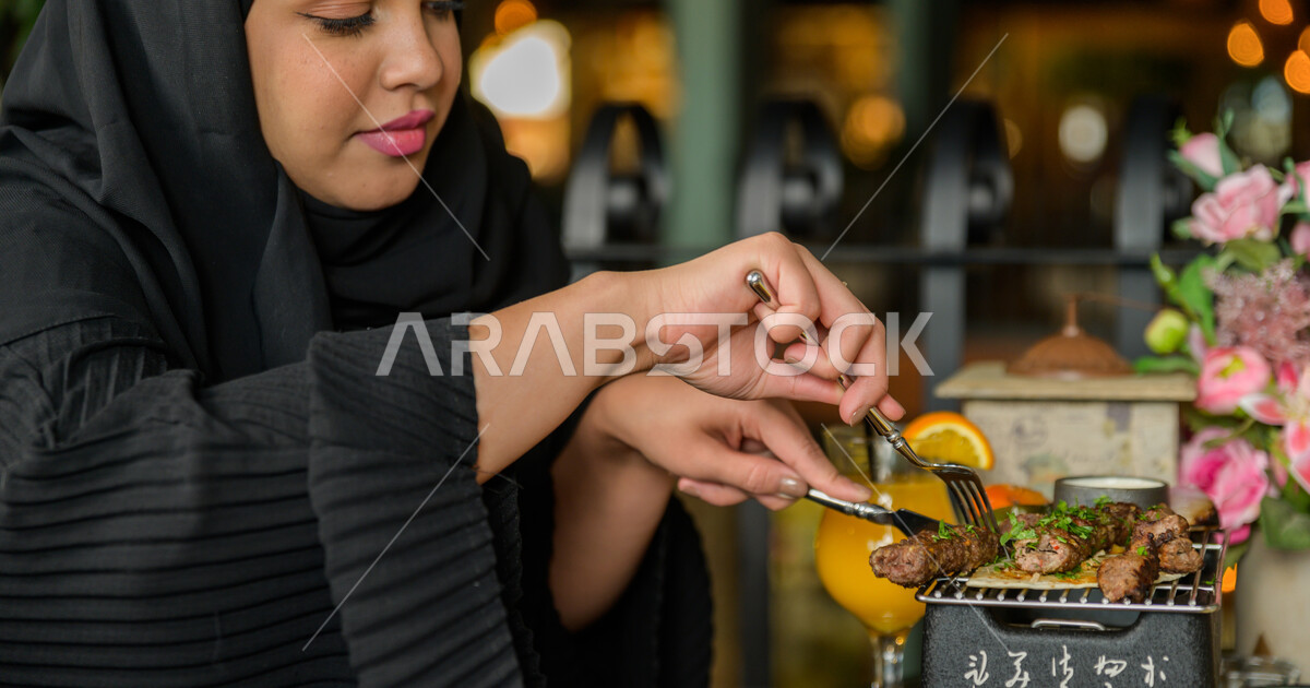 A close-up of a Saudi Arabian Gulf woman eating in the restaurant ...