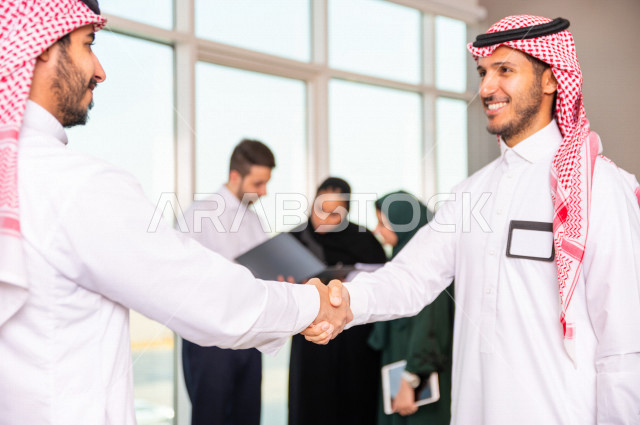 A Saudi Gulf businessman shakes hands with his business partner, and in ...
