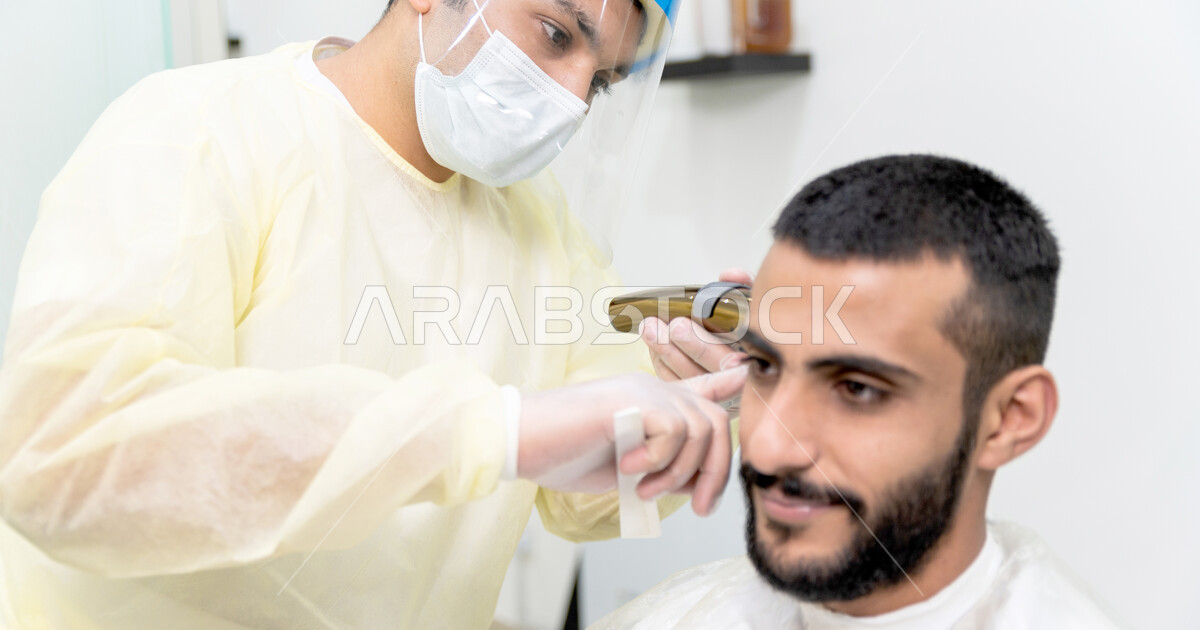 A Saudi Arabian Gulf man visits a barber shop. The barber uses the ...