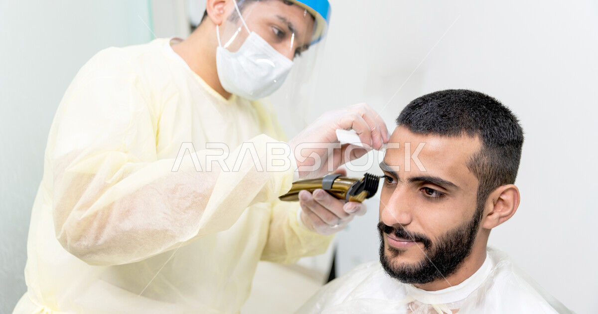 A Saudi Arabian Gulf man visits a barber shop. The barber uses the ...