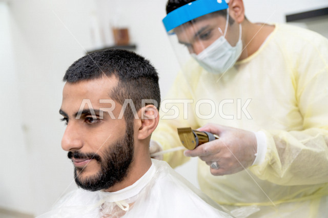 A Saudi Arabian Gulf man visits a barber shop. The barber uses the ...