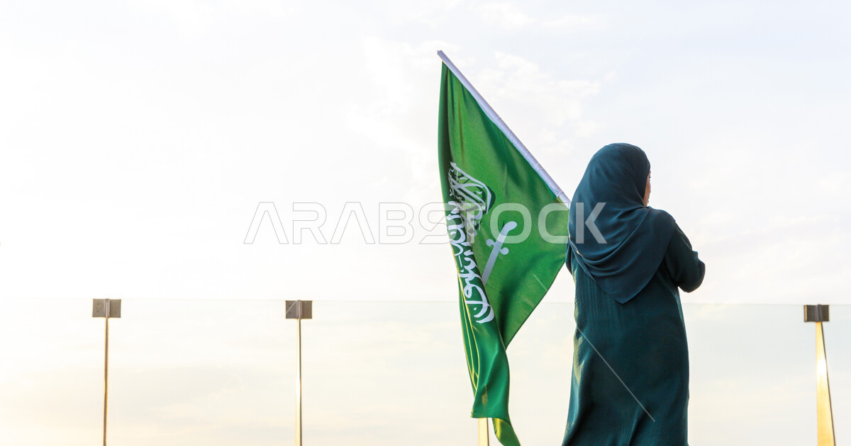 A young Saudi woman from the Gulf, wearing an abaya and hijab, wears ...