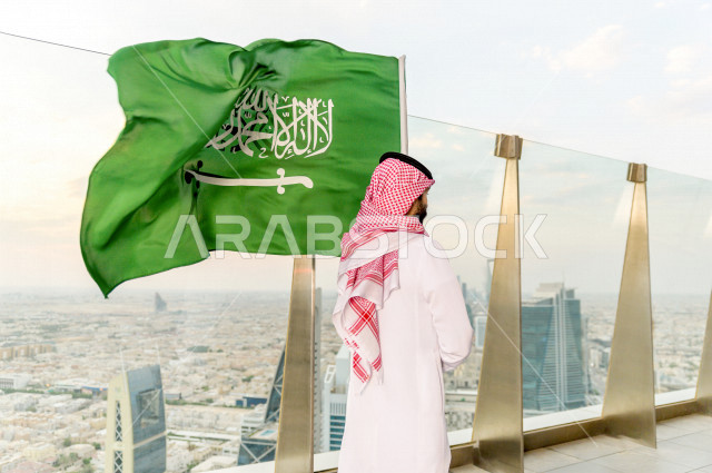 A young Saudi Arabian Gulf dressed in traditional Saudi dress, holding ...
