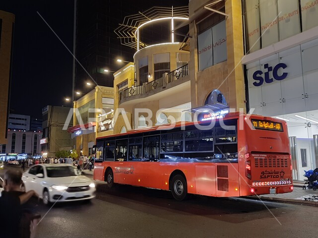 Red Jeddah buses, car traffic on the roads and streets of the historic ...