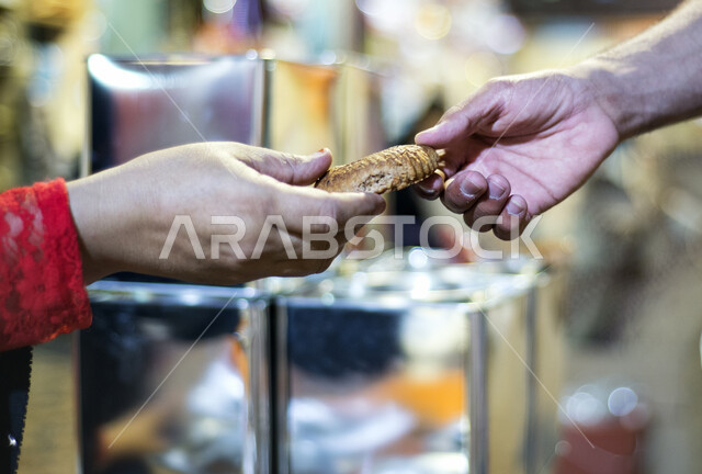 A close-up of a woman's hand giving a man a biscuit, Saudi Arabia's ...