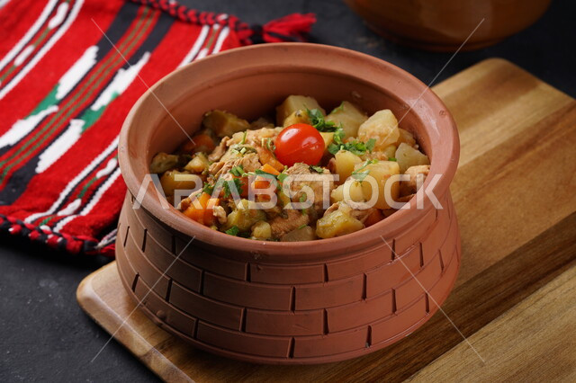 A pottery dish of potatoes with vegetables and delicious meat on a ...