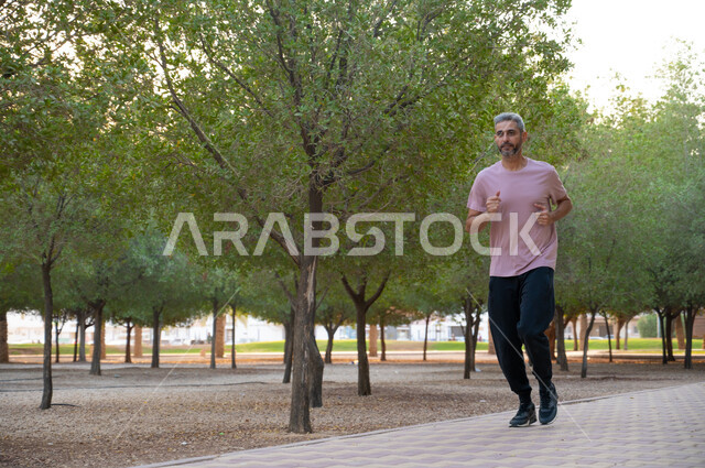 Fitness and physical health, walking in a public park, an elderly Saudi ...
