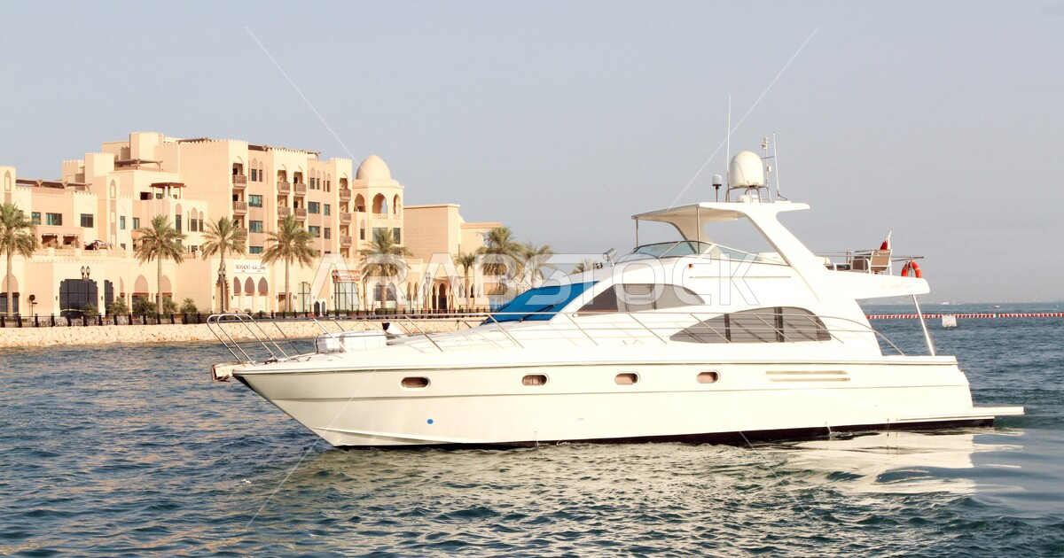 يخت فاخر وسط البحر في خليج اللؤلؤ في قطر، المنتجعات والمباني المطلة على ...