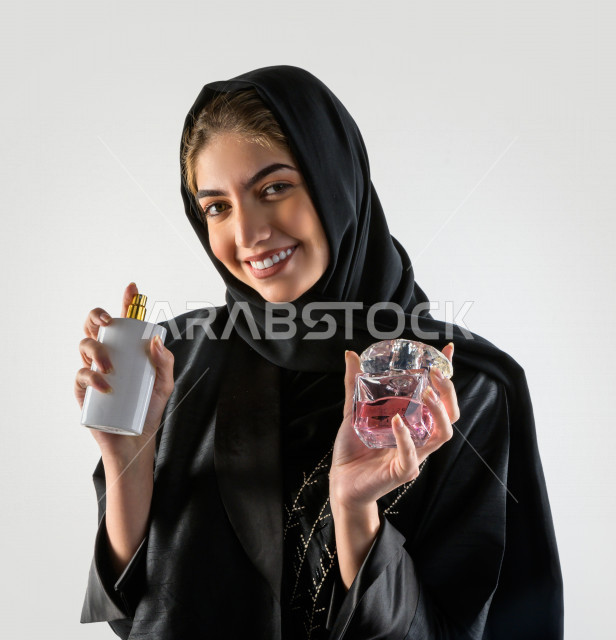 Portrait of a happy Saudi Arabian Gulf woman, using a set of perfumes ...