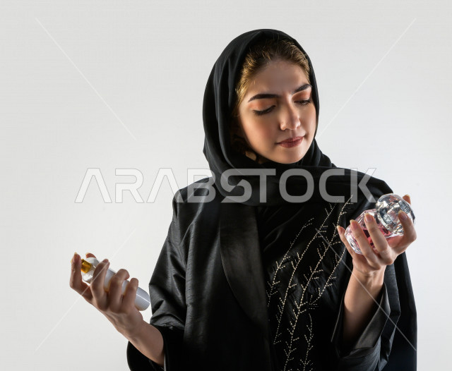 Portrait of a happy Saudi Arabian Gulf woman, using a set of perfumes ...