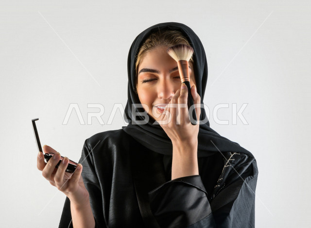 Portrait of a happy Saudi Arabian Gulf woman, who uses a set of ...