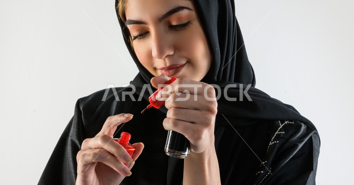 Portrait of a happy Saudi Arabian Gulf woman, using nail polish, a set ...