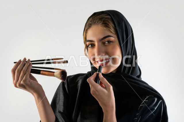 Portrait of a happy Saudi Arabian Gulf woman, who uses a set of ...
