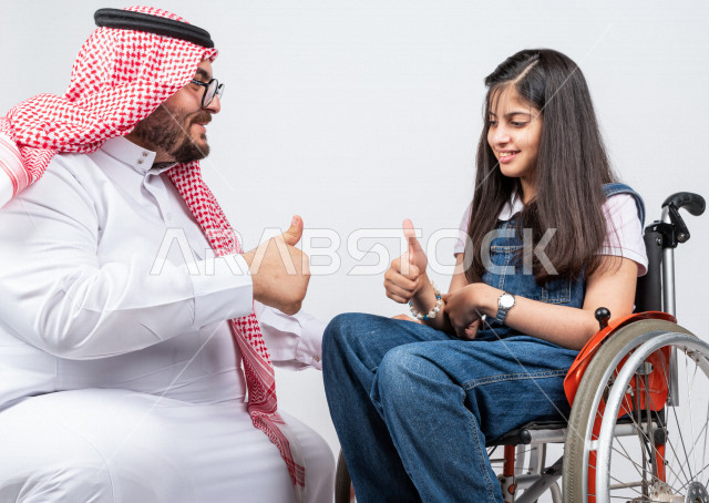 Portrait of a Saudi Arabian girl in a wheelchair with her father, with ...