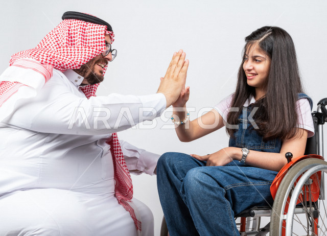 Portrait of a Saudi Arabian girl in a wheelchair with her father, with ...