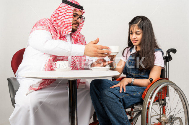 Portrait of a Saudi Arabian Gulf child in a wheelchair with her father ...