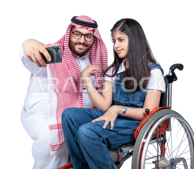 Portrait of a Saudi Arabian Gulf child in a wheelchair with her father ...