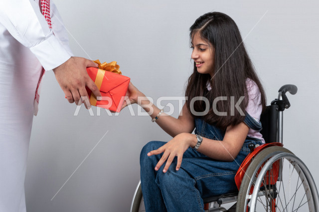 Portrait of a Saudi Arabian Gulf girl in a wheelchair with her father ...