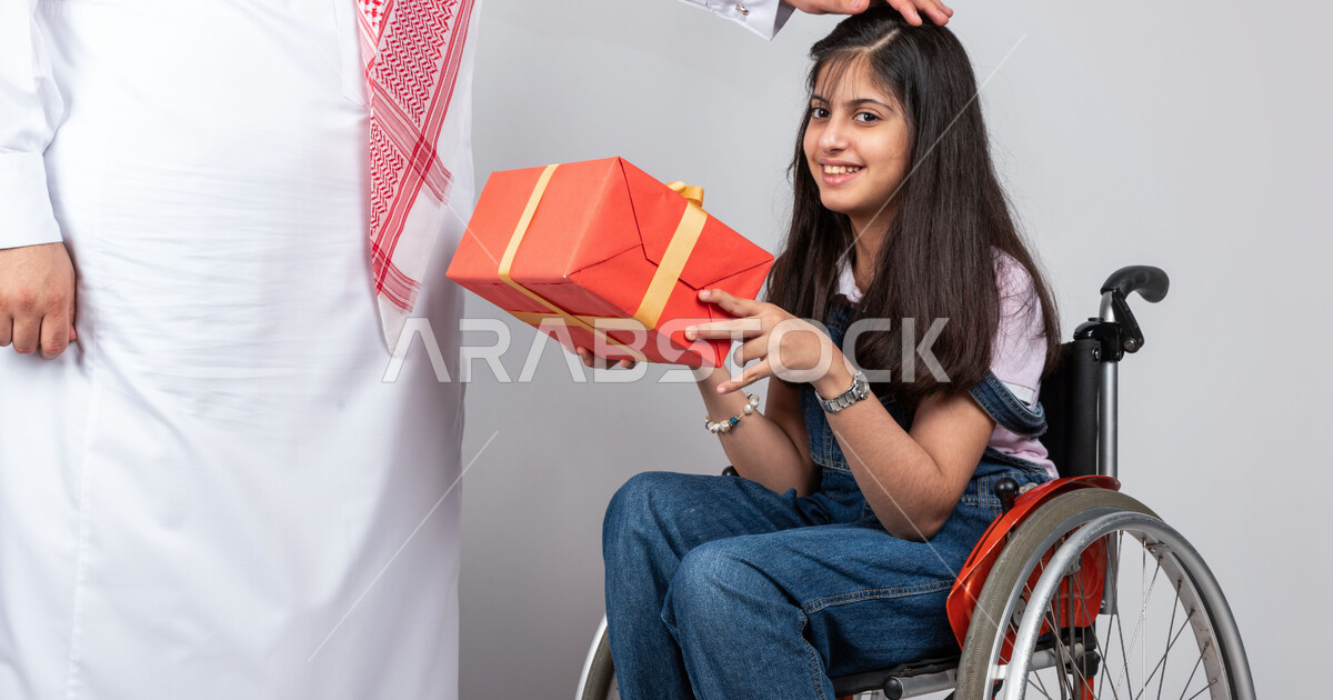 Portrait of a Saudi Arabian Gulf girl in a wheelchair with her father ...