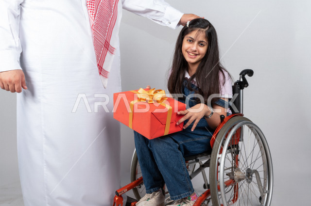 Portrait of a Saudi Arabian Gulf girl in a wheelchair with her father ...