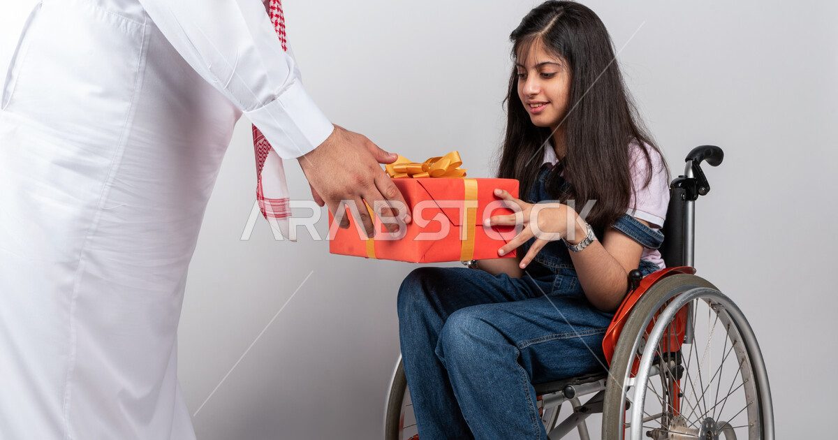 Portrait of a Saudi Arabian Gulf girl in a wheelchair with her father ...