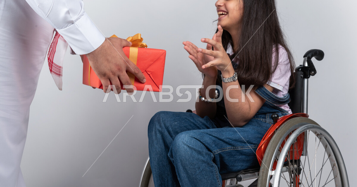 Portrait of a Saudi Arabian Gulf girl in a wheelchair with her father ...