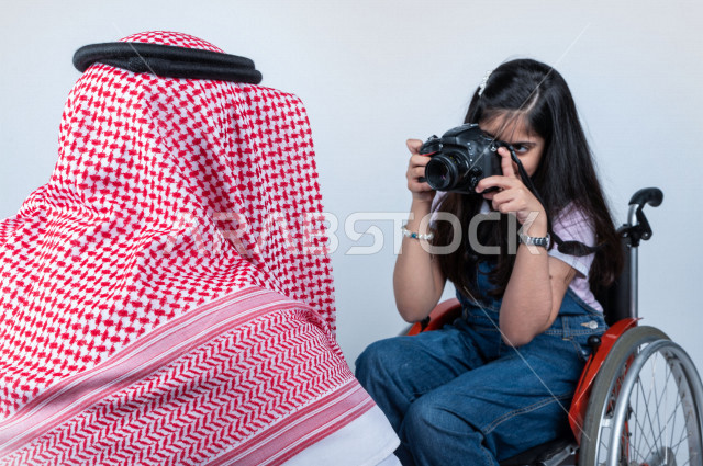 Portrait of a Saudi Arabian girl in a wheelchair with her father, ready ...