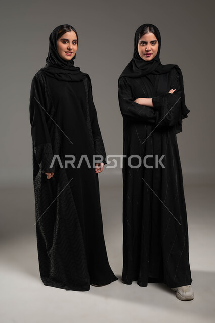 Looking at the camera with crossed hands, portrait of two veiled Saudi ...