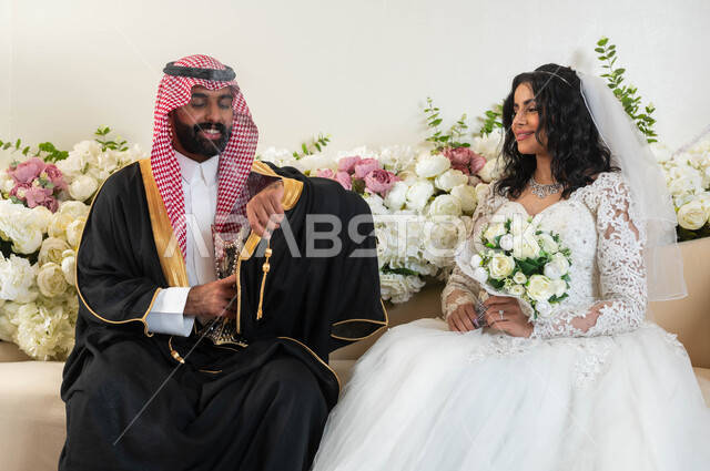 A bride wearing a white wedding dress, a Saudi Arabian Gulf groom ...