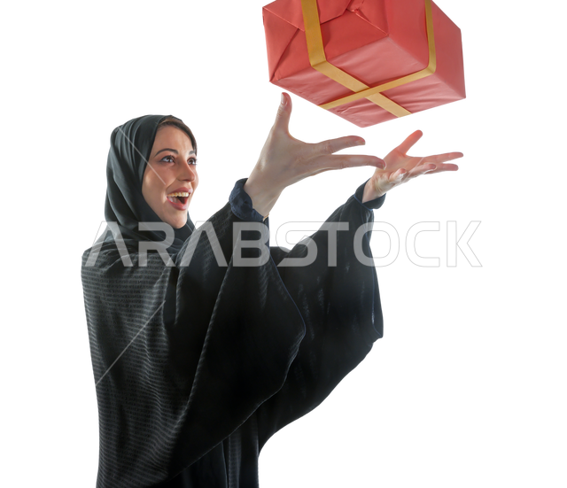 Portrait of a Saudi Arabian Gulf woman carrying a large gift box ...