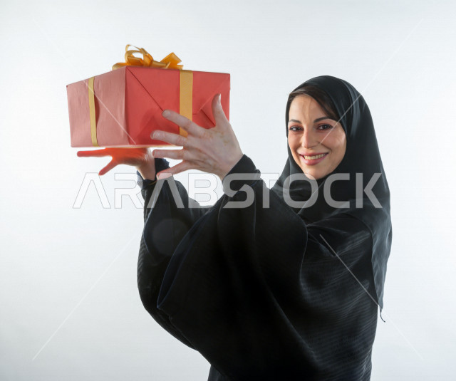 Portrait of a Saudi Arabian Gulf woman carrying a large gift box ...