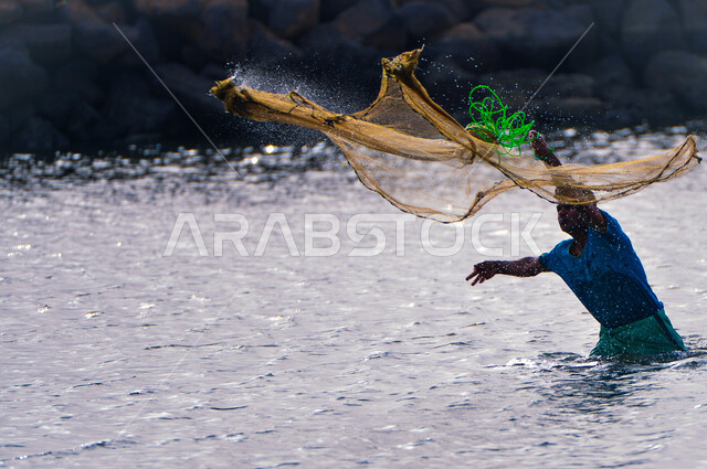 A Saudi Gulf Arab fisherman throwing a fishing net at Jazan Beach, the ...