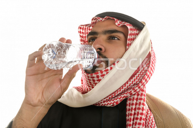 Portrait of a Saudi Arabian Gulf man drinking water, wearing winter ...