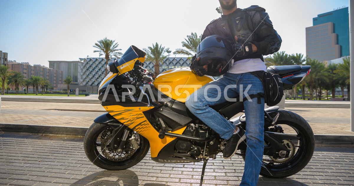 A young Saudi Arab driver, driving his motorcycle, wearing a protection ...
