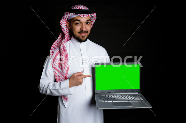 Portrait of a Saudi Arabian Gulf man holding a laptop with a green ...