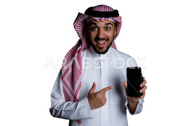 Portrait of a young saudi Gulf Arab pointing to cell phone in amazement ...