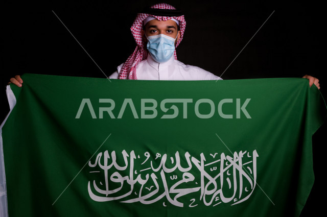 Portrait of a Saudi Arabian Gulf man wearing a medical mask and holding ...