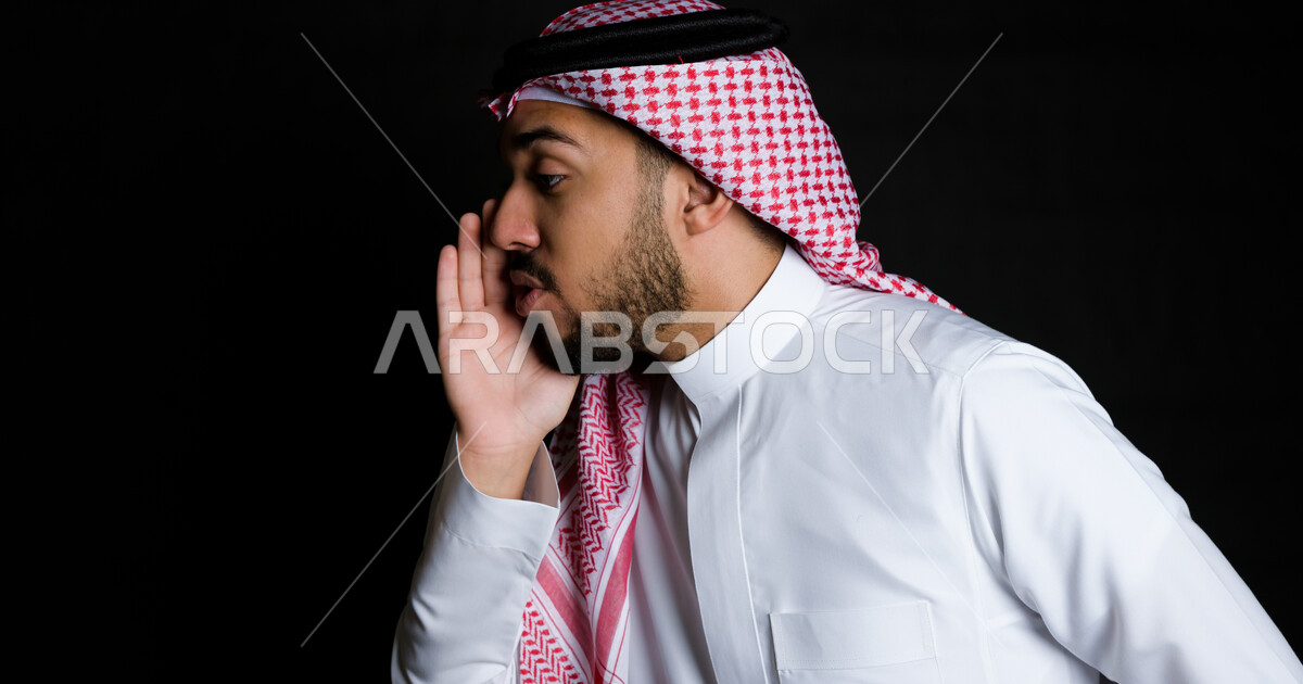Portrait of a young Saudi Arabian Gulf Arab whispering secretly behind ...