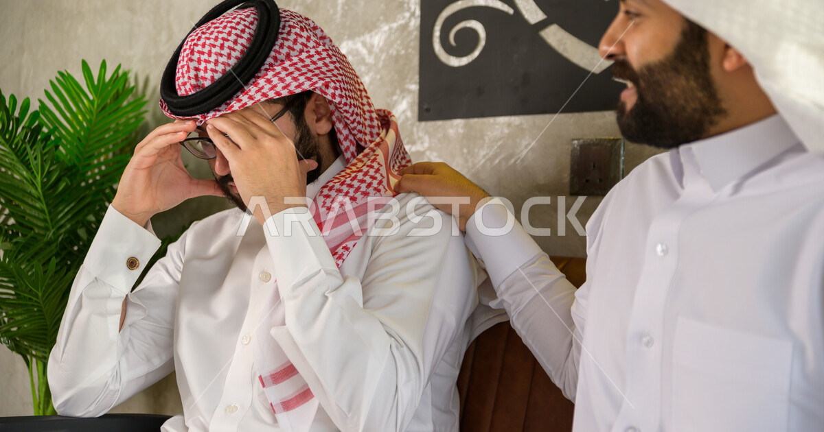 Saudi friends sitting in a cafe , a sad youth man with his friend ...