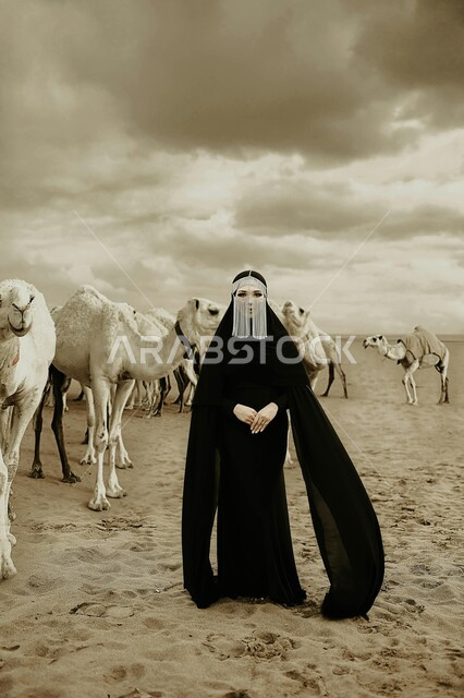 A Saudi Arabian Gulf camel herder wearing an abaya and a white burqa ...