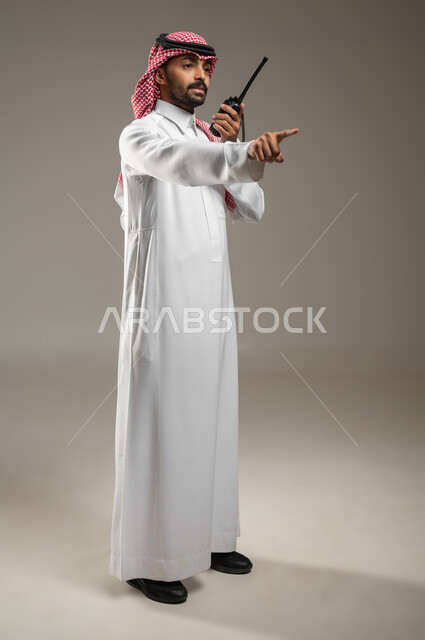 Portrait of a Saudi Arabian Gulf man wearing Saudi uniform, using a ...