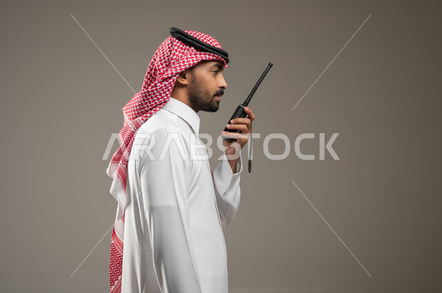 Talking on a walkie-talkie, a close-up portrait of a Saudi Gulf Arab ...