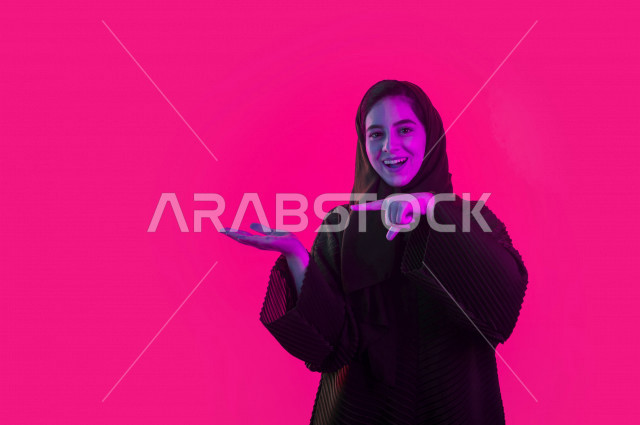 Portrait of a happy Saudi Arabian Gulf woman, pointing her finger to ...
