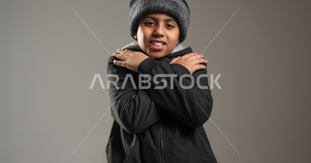 الأجواء الشتوية في السعودية، النظر الى الكاميرا بايماءات وجه ويدين تدل على البرد الشديد، ملابس ...