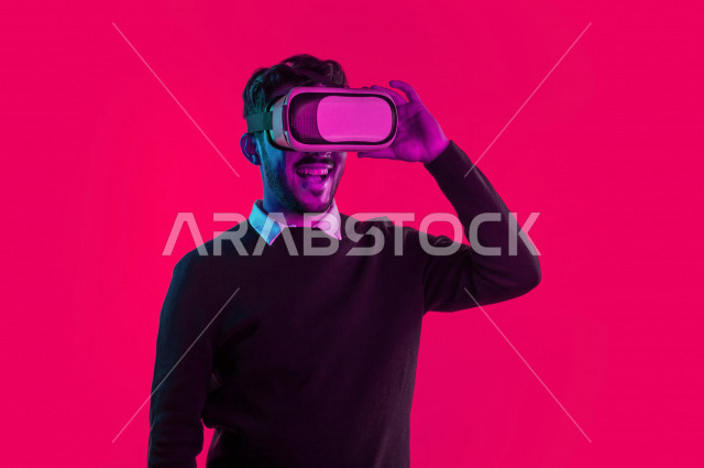 Portrait of a happy Saudi Gulf man, putting up a VR Box, face and hands ...