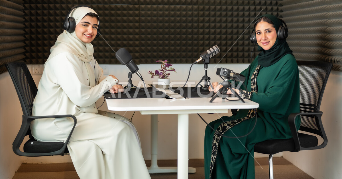 Looking at the camera with happy gestures, two veiled, smiling Gulf ...