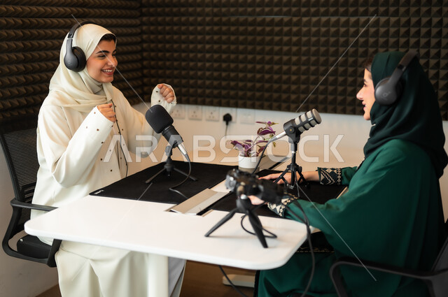 Using modern technologies, two smiling, veiled Arab Gulf women wearing ...