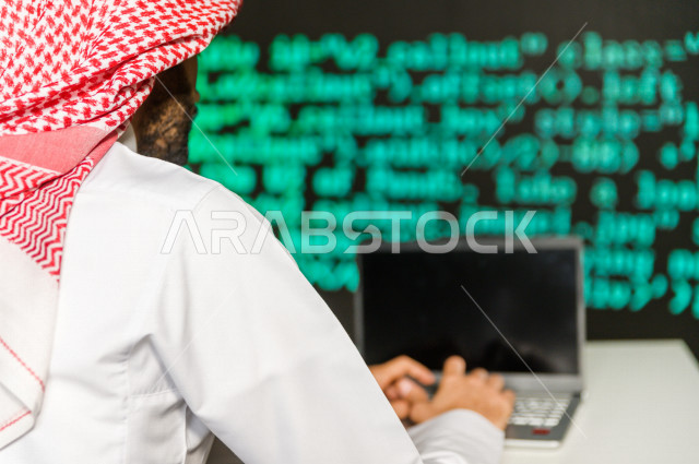 A young Saudi Gulf Arab working as a web developer, using a variety of ...