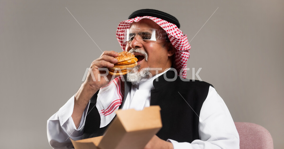 Enjoying eating fast food, a close-up portrait of a Saudi Gulf Arab man ...