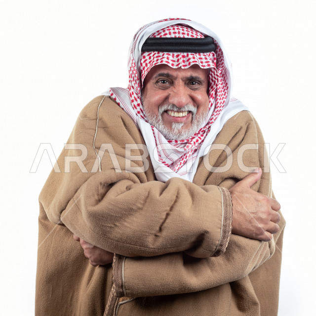 Portrait of an old Saudi Arab man feeling cold, wearing a Saudi bisht ...